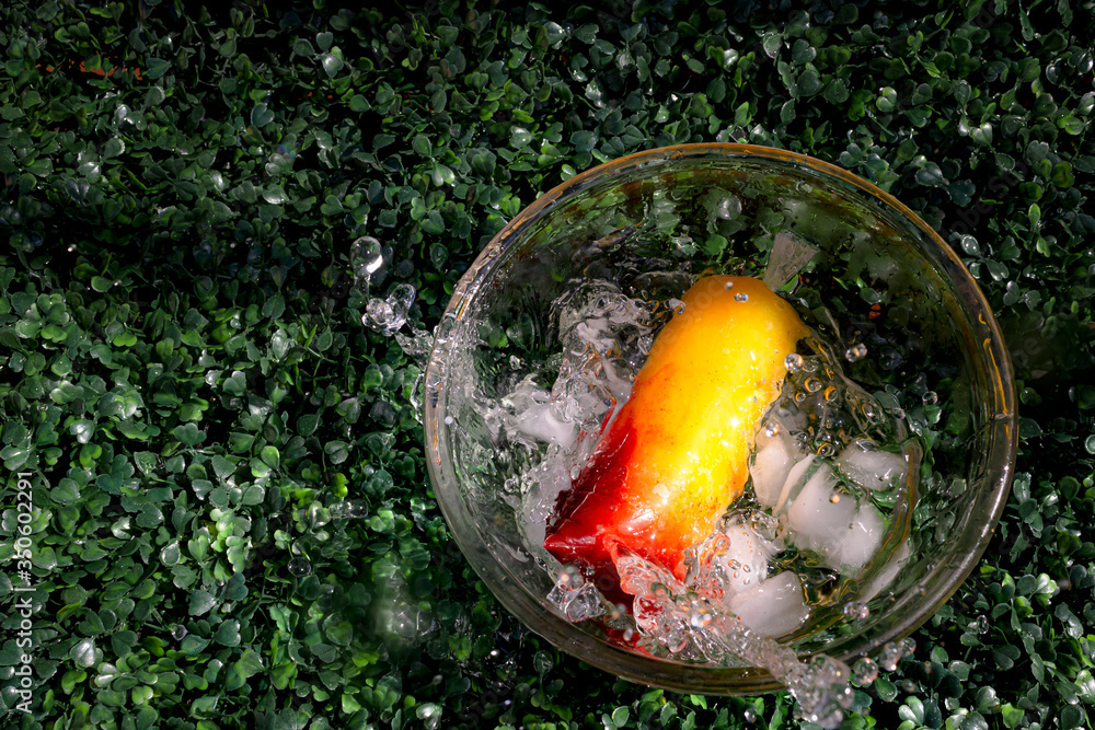 Bolis de mango con chile chamoy cayendo en agua con hielos naranjú ...