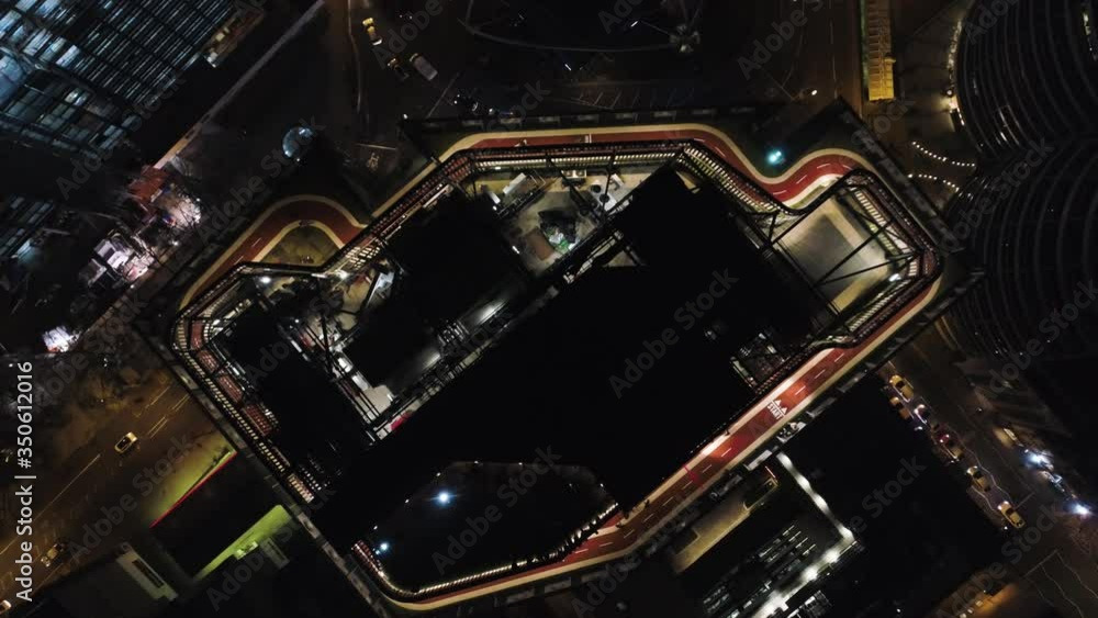 Group of runners running around rooftop running track at night birds ...