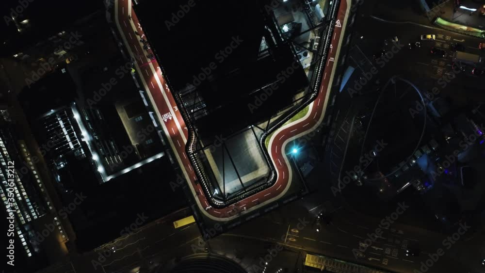 Group of runners starting race around rooftop running track at night ...