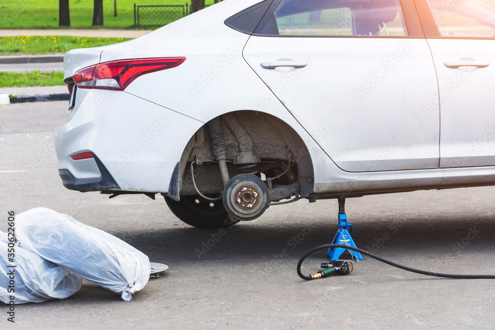 Replacing tires on wheels, a car without a rear wheel on a jack ...