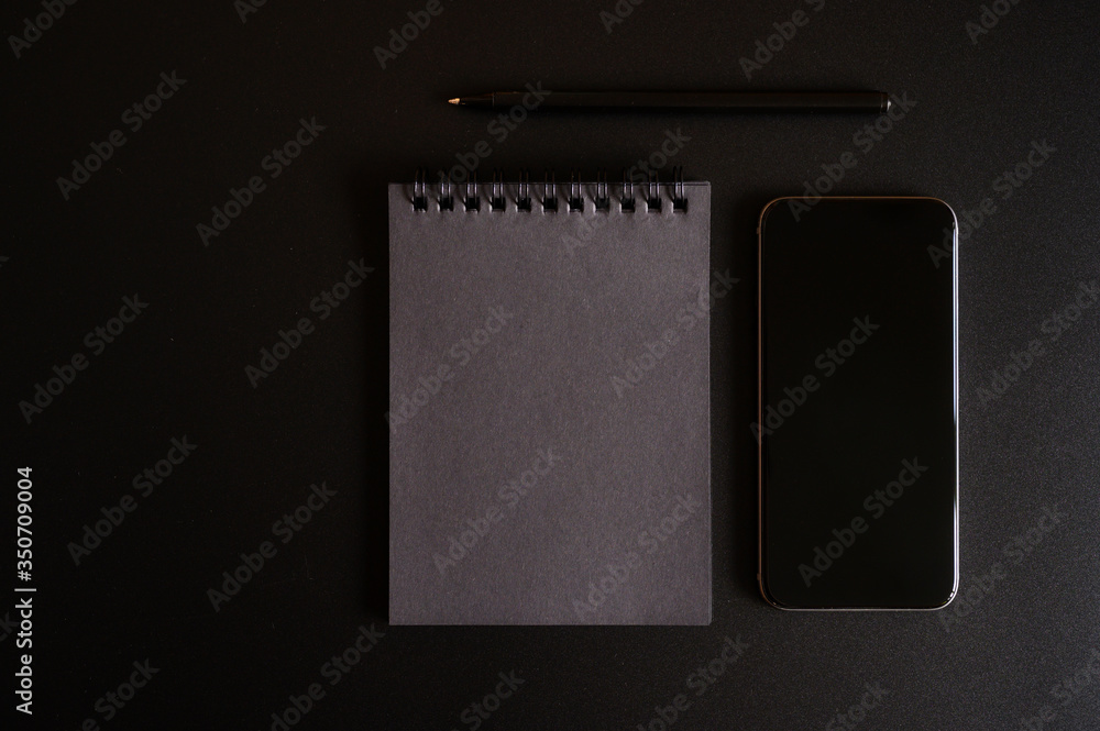 notebook on a spring with black sheets, and a pen, and mobile phone on ...