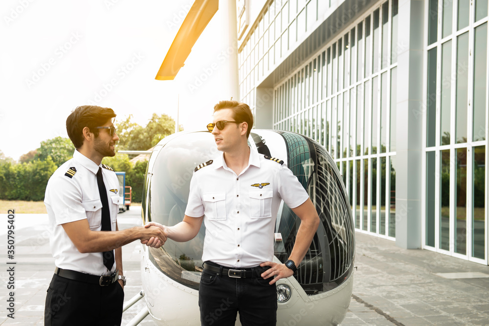 Teamwork of young caucasian handsome man in pilot uniform shaking hands ...