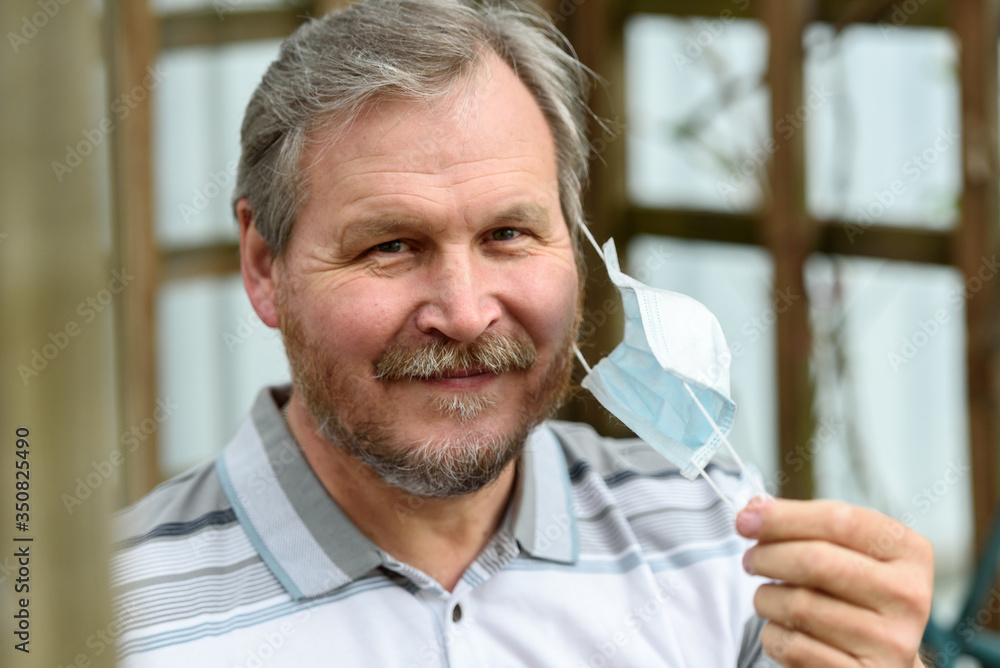 The man joyfully removes the medical mask from his face. End of the ...