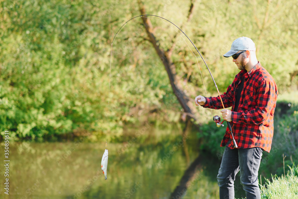 Man relaxing and fishing by lakeside. Weekends made for fishing. Fisher ...