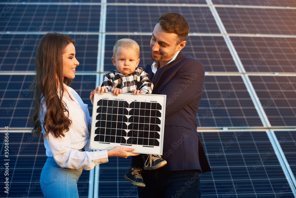 Young happy family on the background of solar panels. A man, woman and ...