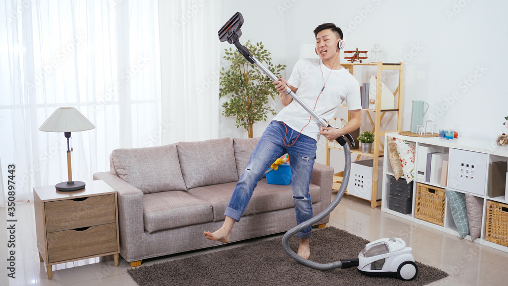 household cleaning fun young man sweeping floor with earphone is ...
