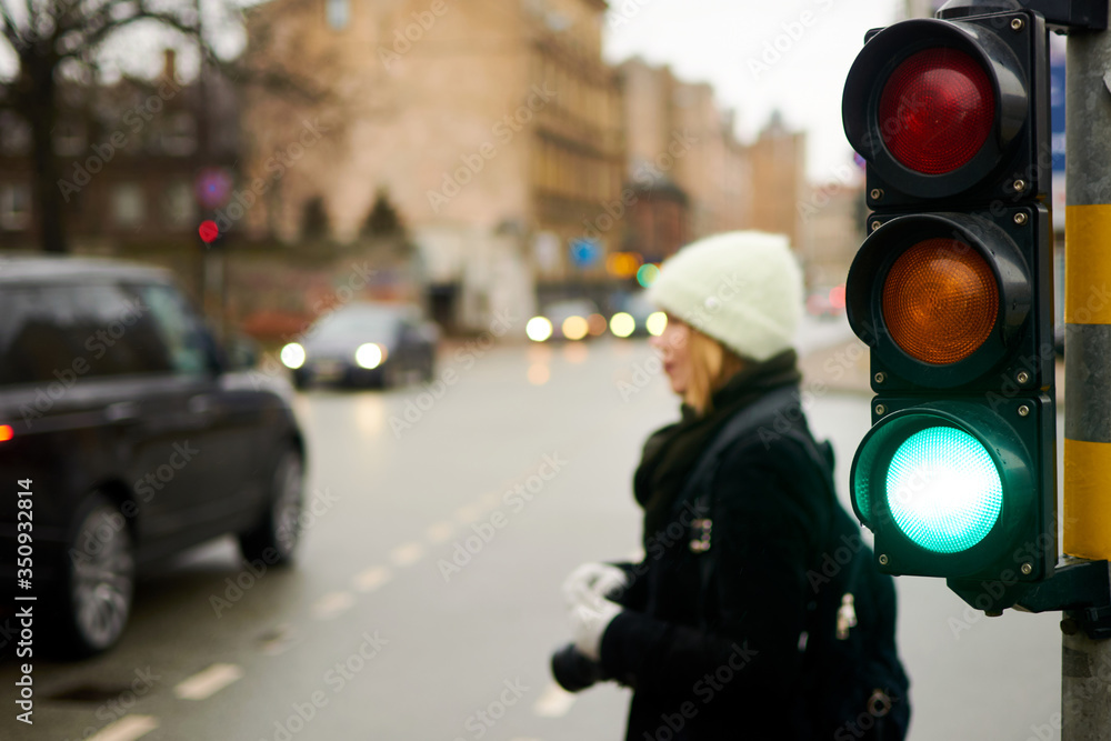 Foto de Green traffic light on a city street. A woman is waiting at a ...