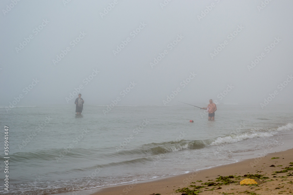 Fishermen catch fish in the fog on the beach Stock Photo | Adobe Stock