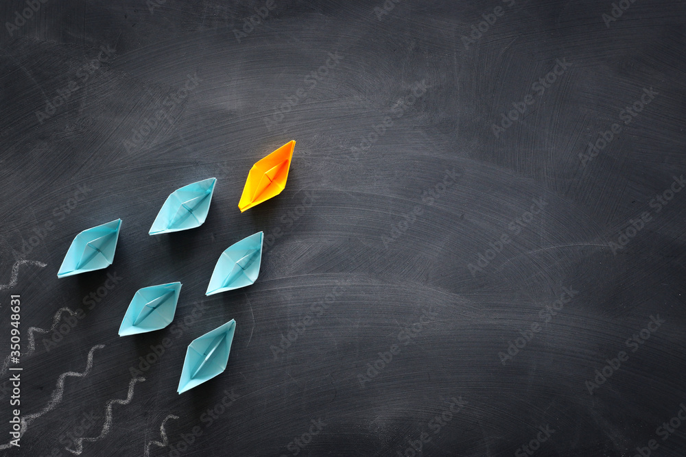 Leadership banner concept with paper boat on blackboard background. One ...