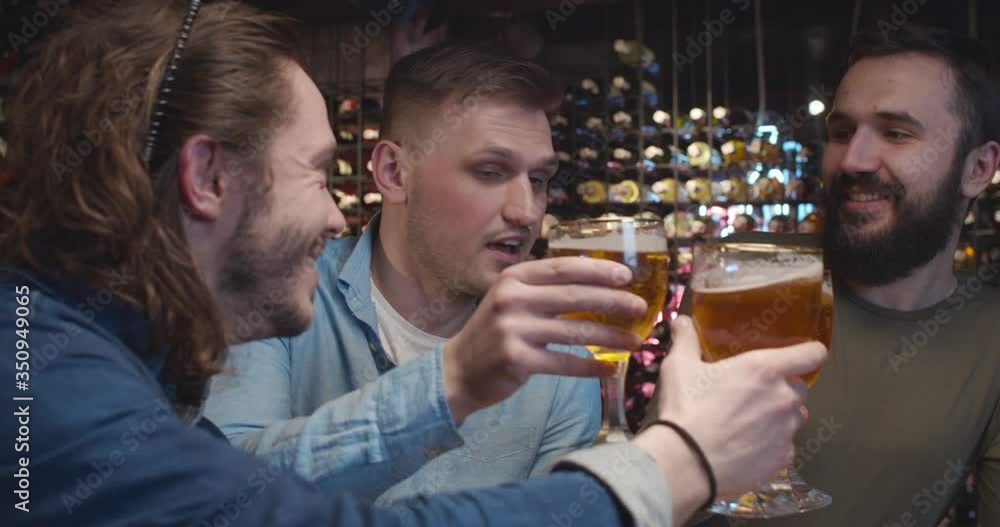 Caucasian male friends cheering up in bar when watching sport game ...