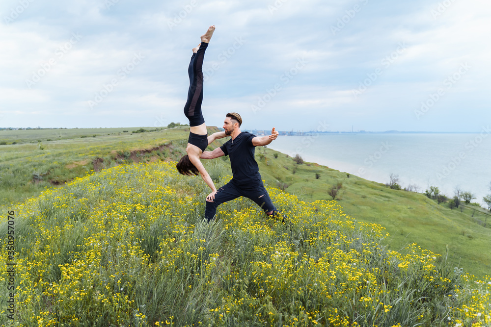 Two sportsmen practicing acro yoga together outdoors in the evening ...
