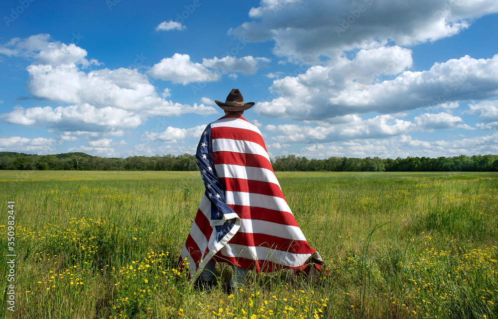 Man wearing cowboy hat standing in grassy agricultural field with ...