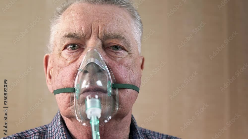 Portrait of an elderly man with COPD in an oxygen mask who is breathing ...
