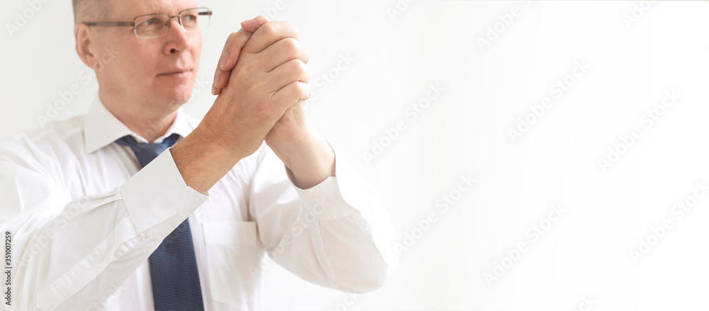 A glad adult businessman in white shirt and tie holding his hands ...