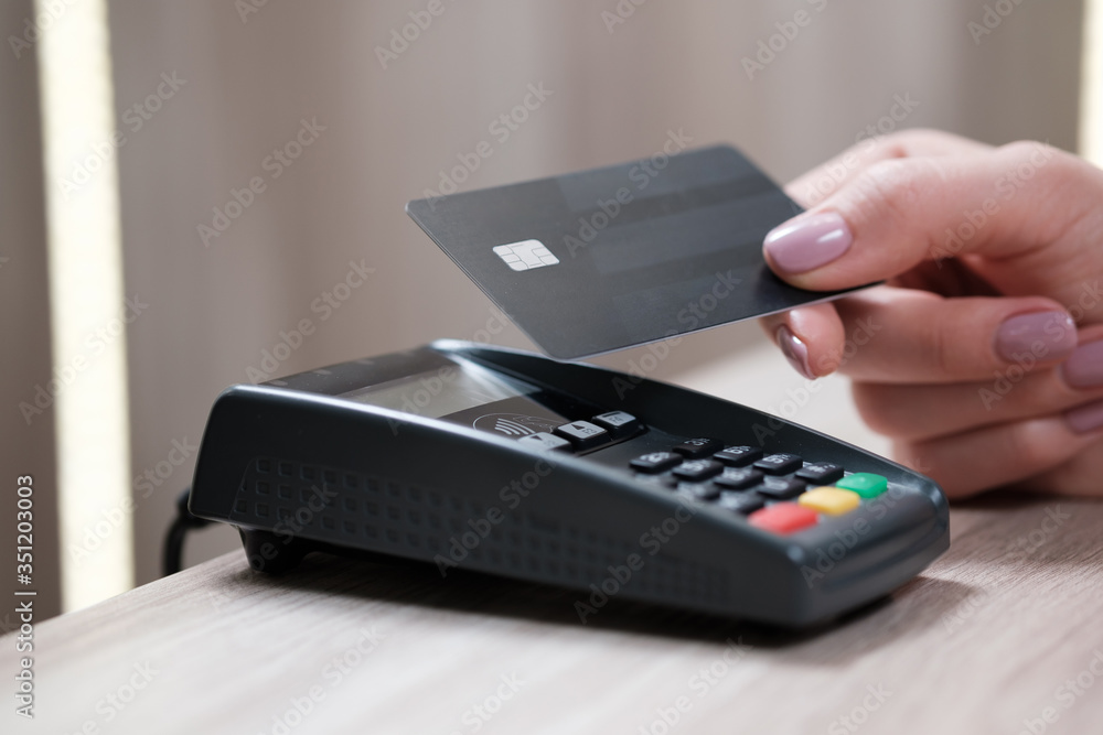Hand of customer paying with contactless credit card with NFC ...