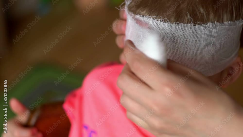 mother bandages the child's head. dressing an injured child's head. A ...