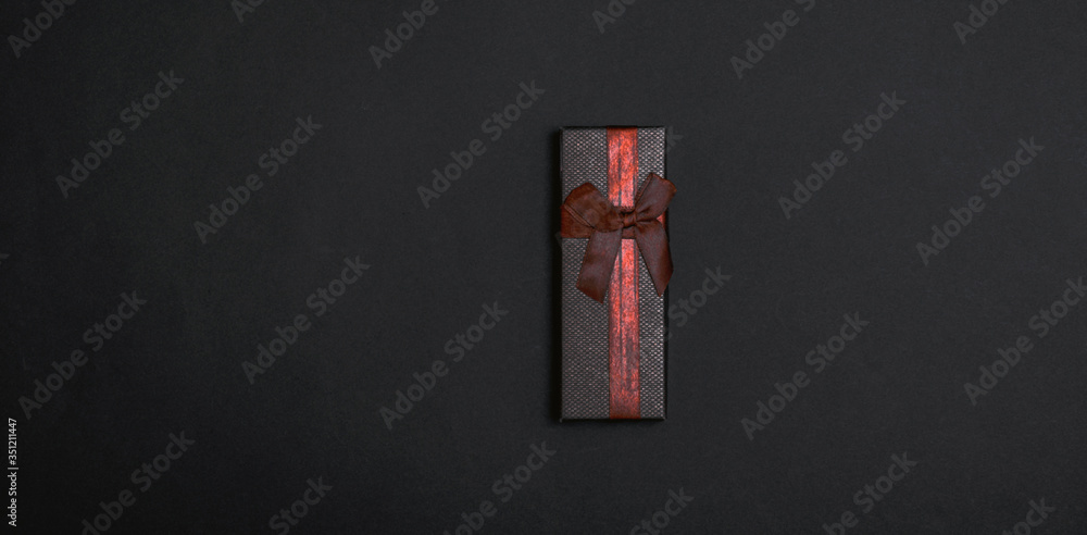 One single gift wrapped in dark brown paper with a bow of packthread on ...
