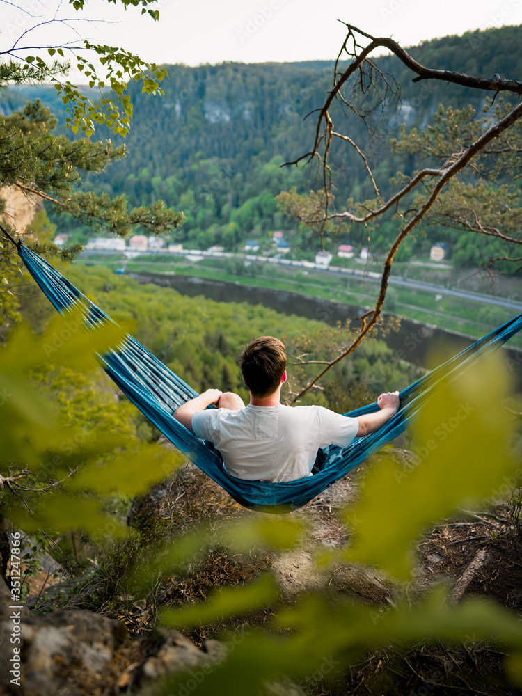Adventurer lying in hammock on top of mountain, between two trees with ...