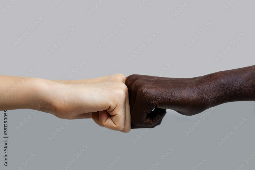 The black African-American hand and the white European hand give a blow ...