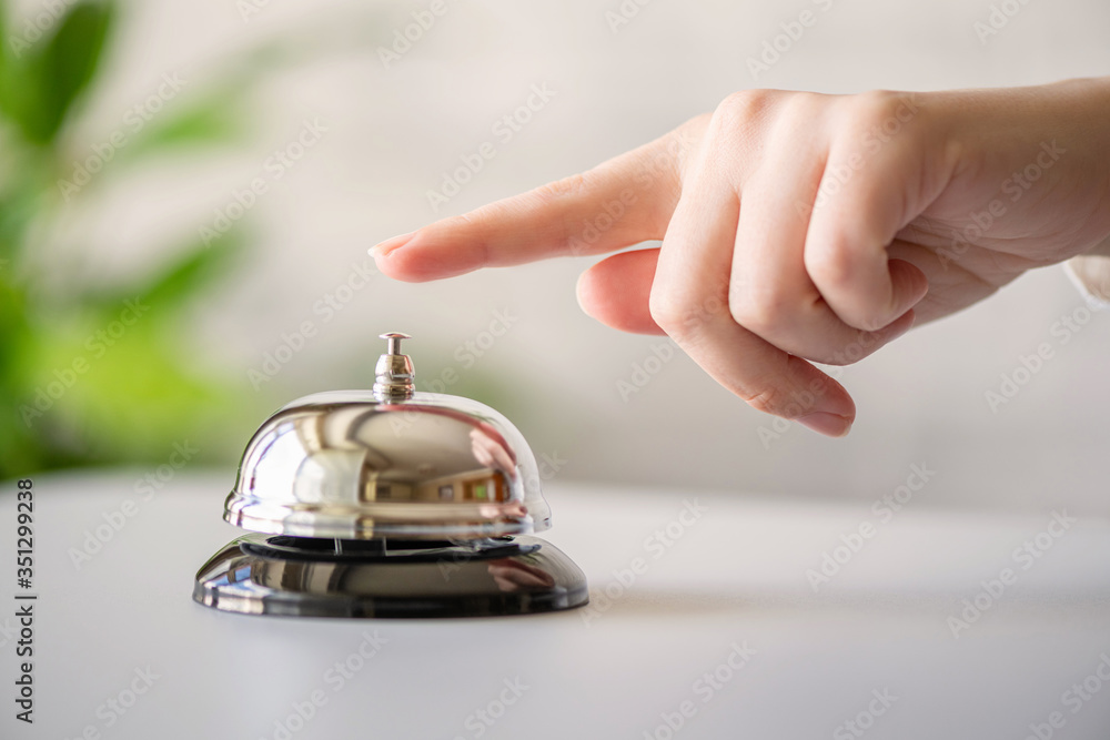 Hand of guest ringing in silver bell. reception desk with copy space ...