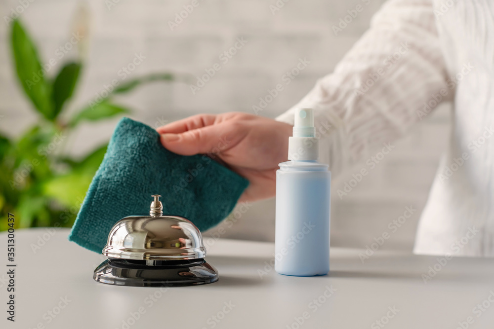 Hand of woman cleaning ringing bell on reception desk. disinfection ...