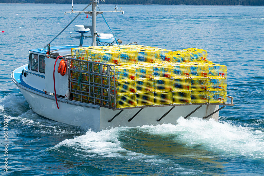 Lobster fishing boat full of yellow lobster traps heading out to see ...