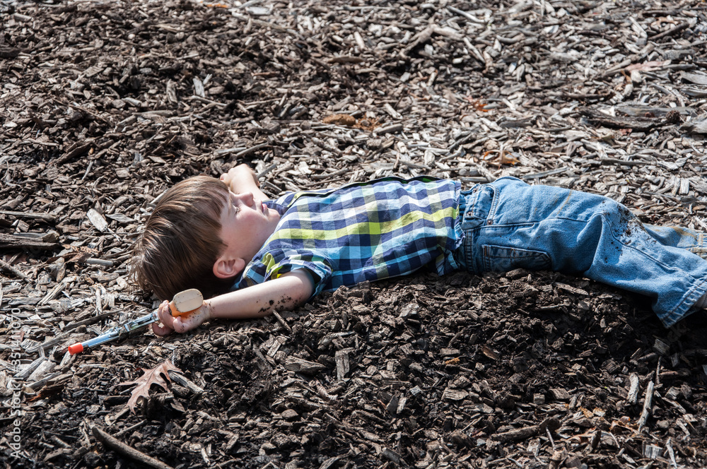Young boy pretending to be dead while playing cowboys and holding a gun ...