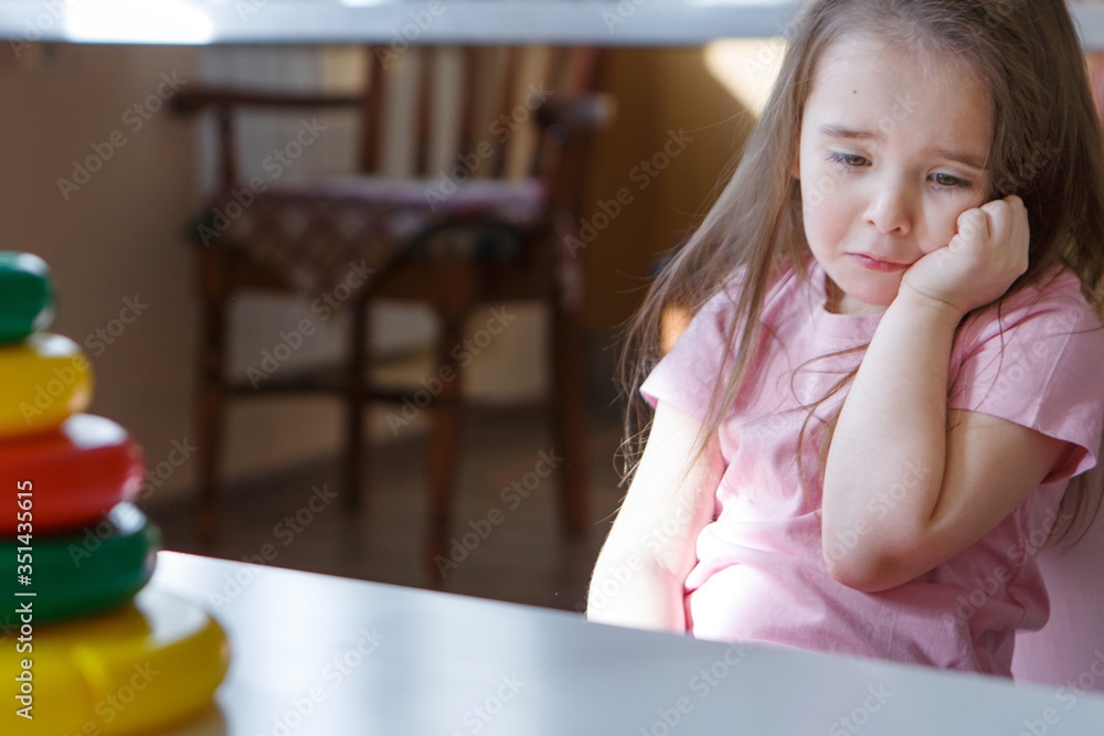 child is bored while collecting tpyramid details of toy, sad face ...