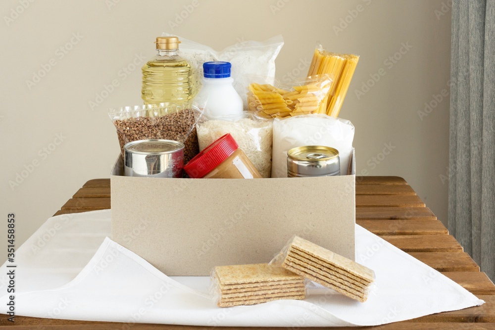 Cardboard box with food on wood table and white napkin. Donation and ...