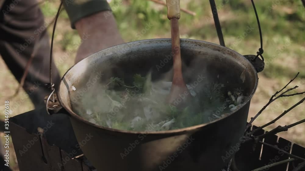 Meat with rice and vegetables is cooked in a cauldron at the stake. The ...