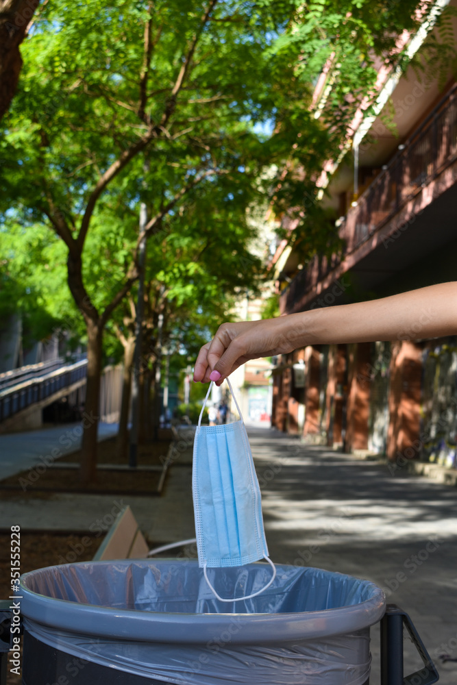 Woman throwing a face mask in the trash as a symbol of leaving the ...
