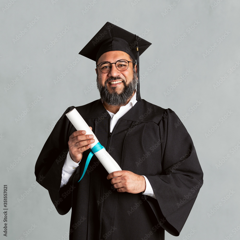 Happy senior man in a graduation gown holding his master's degree ...