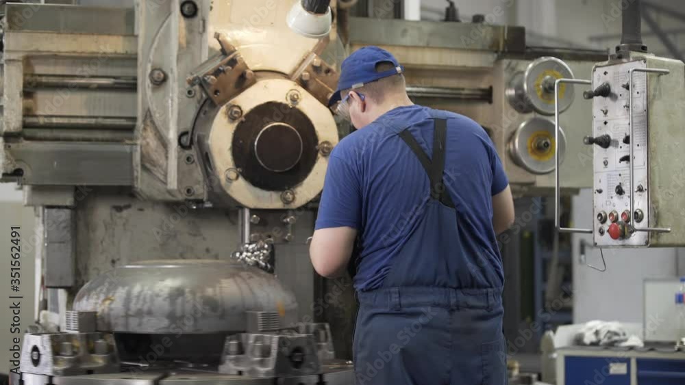 Milling machine operator working in factory workshop. Cutter cuts metal ...