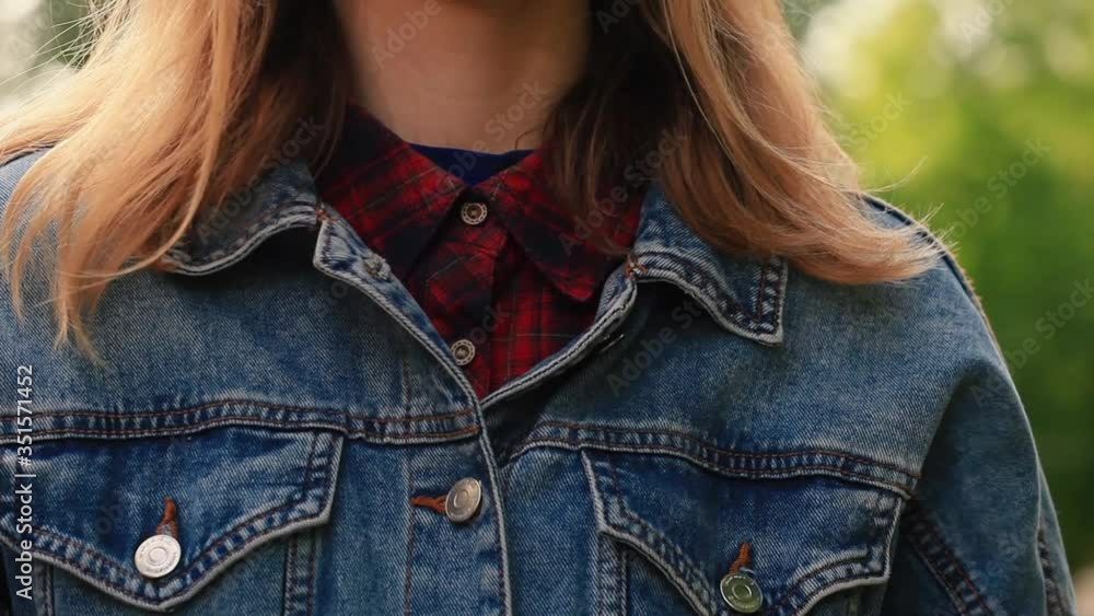 the girl unzips the button of her denim jacket and then zips it back up ...