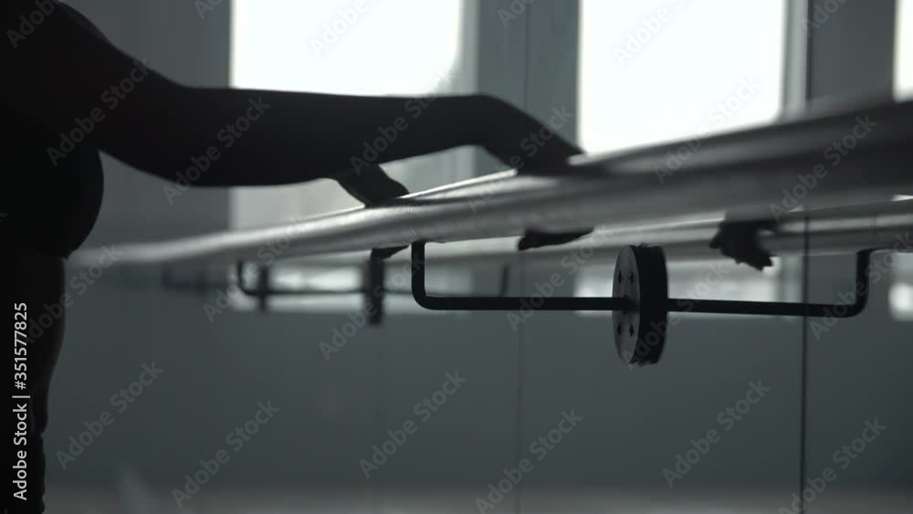 Modern contemporary dancer using dance studio hand rail to warm up and ...