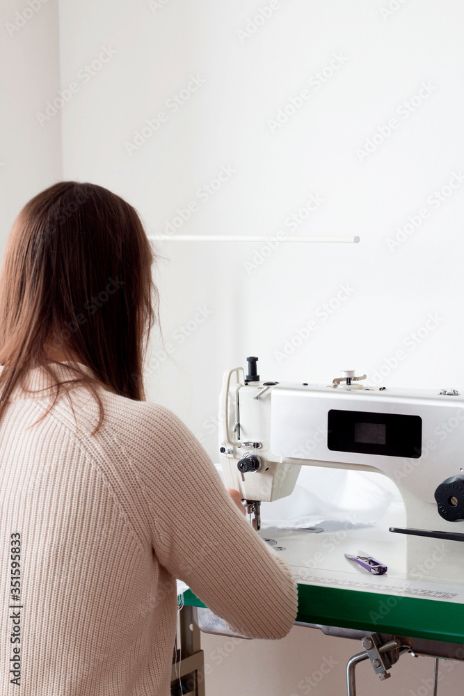 in the atelier of a sewing workshop, a young girl sews a dress on an ...