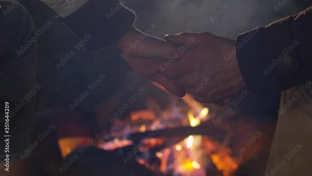 Close up hands of couple on the against the fire. Family sitting hand ...