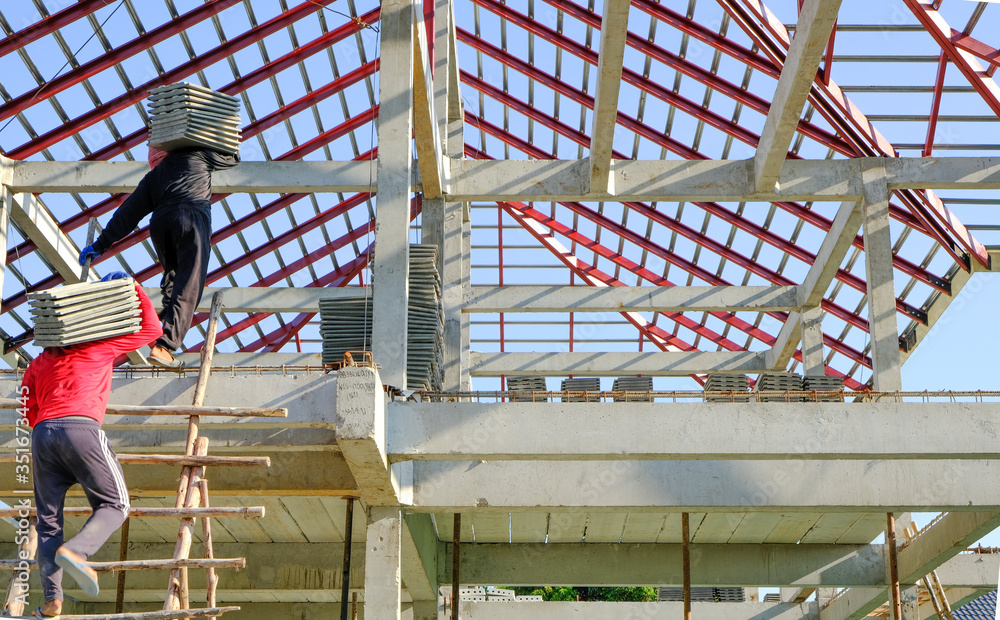 male worker moving lift roof tiles on stair going up to second floor ...