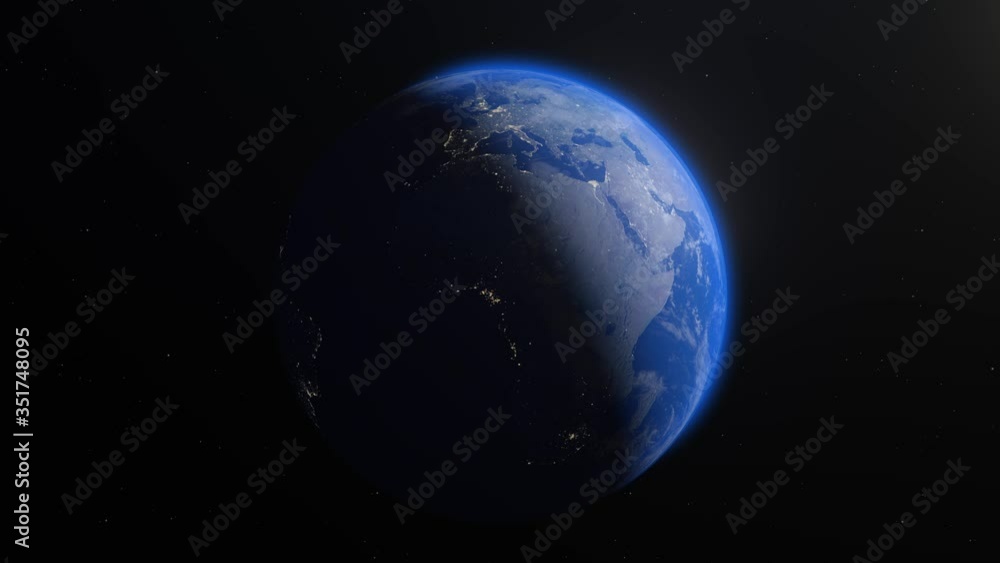 The Earth slowly rotating in space, backlit by the sun with the lights ...