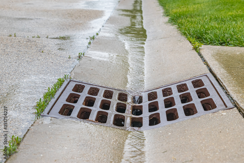 Foto de Closeup of rain water running down street gutter and flowing ...