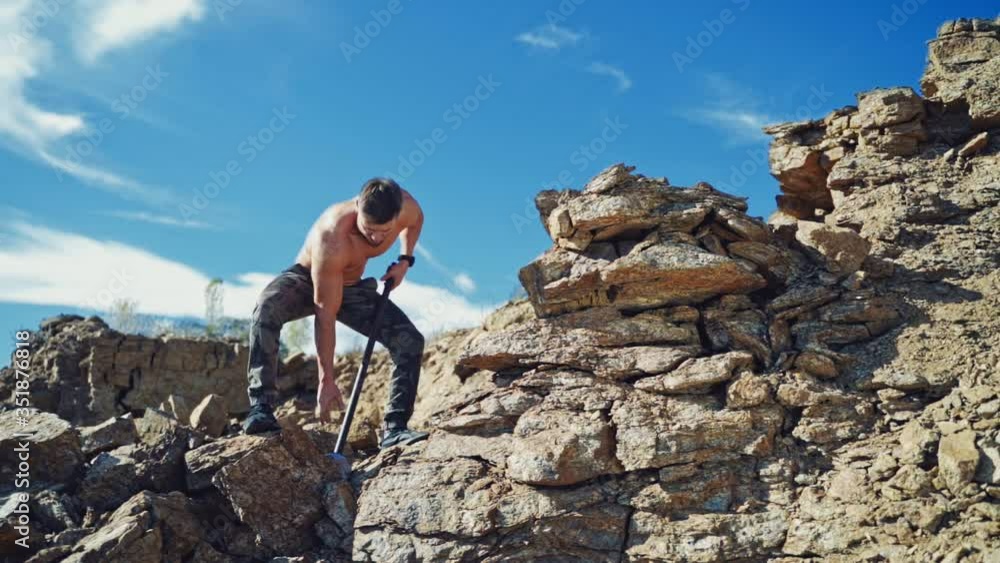 Athletic man exercises with a big hammer in canyon. Muscular man ...