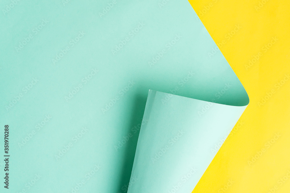 Mock-up paper sheet of pastel turquoise color curved on a yellow ...