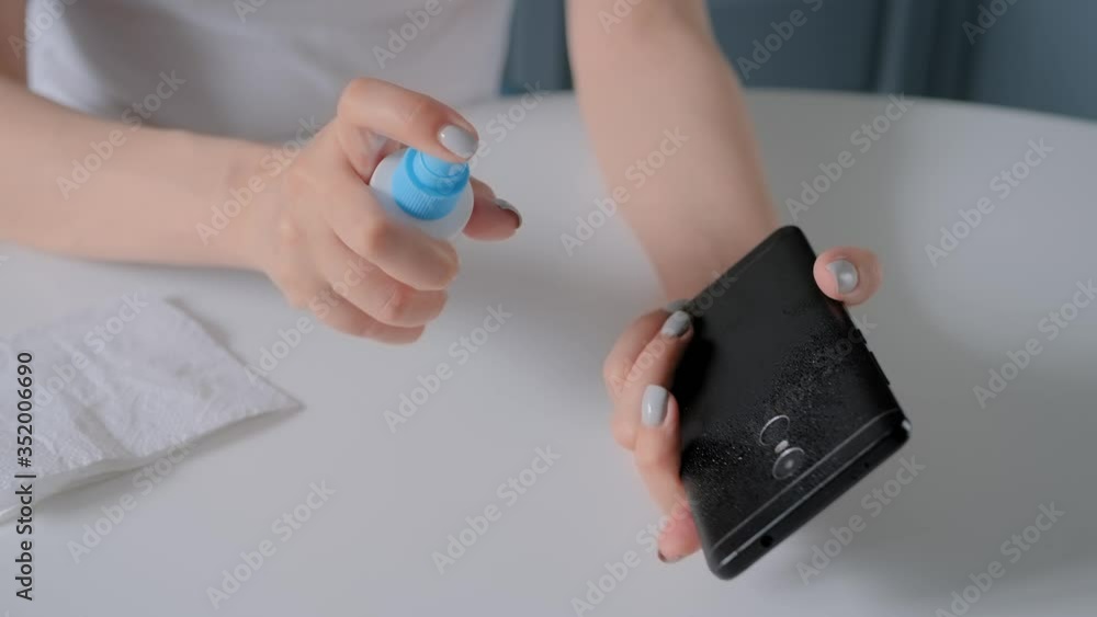 Slow motion: woman spraying antiseptic and cleaning black smartphone ...