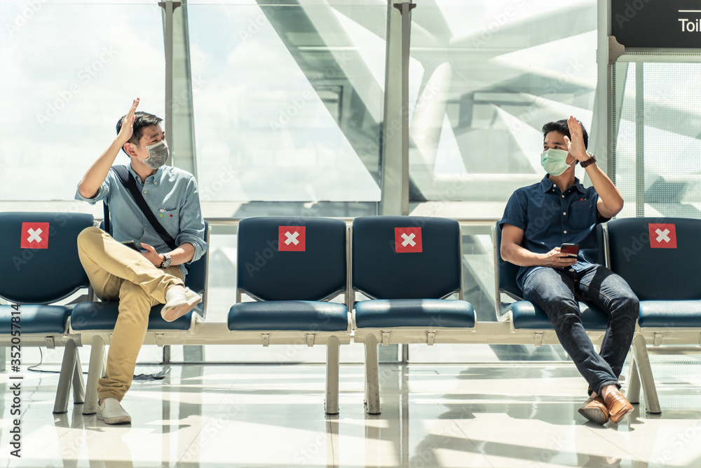 Social distancing, two men wearing face mask sitting keeping distance ...