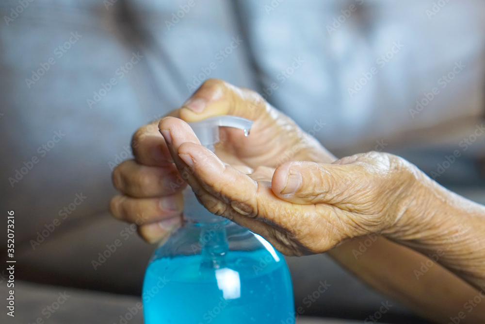 Old lady washing hands with alcohol gel or antibacterial soap sanitizer ...