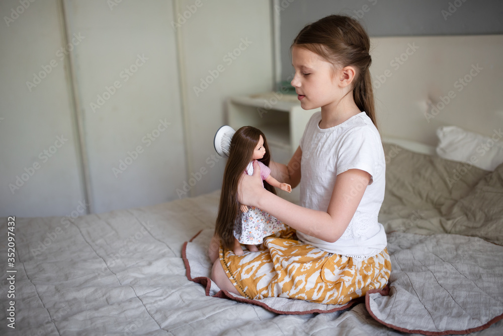 Foto de Caucasian girl combing a doll with long hair, a girl playing ...