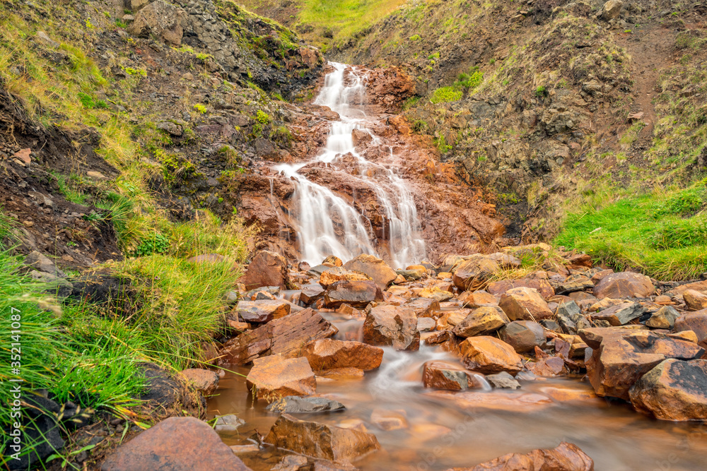 Red rocks and beautiful exotic waterfall cascade at Hvitserkur in ...