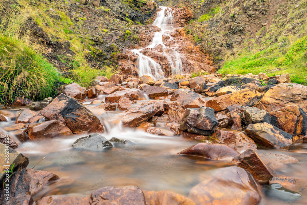 Red rocks and beautiful exotic waterfall cascade at Hvitserkur in ...
