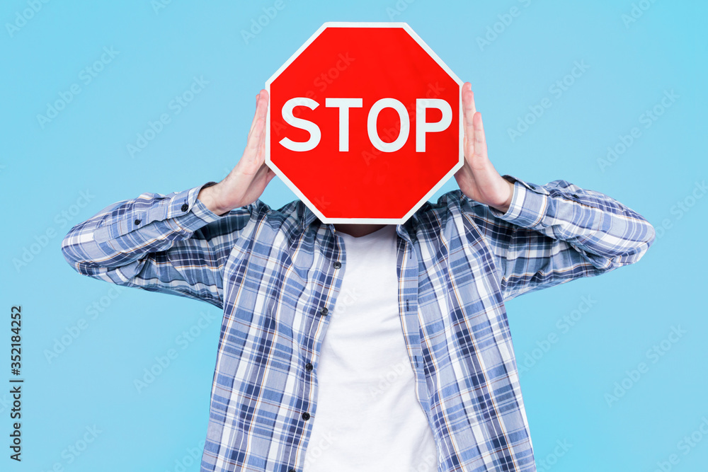 Man is holding red prohibition road sign stop in front of face on blue ...