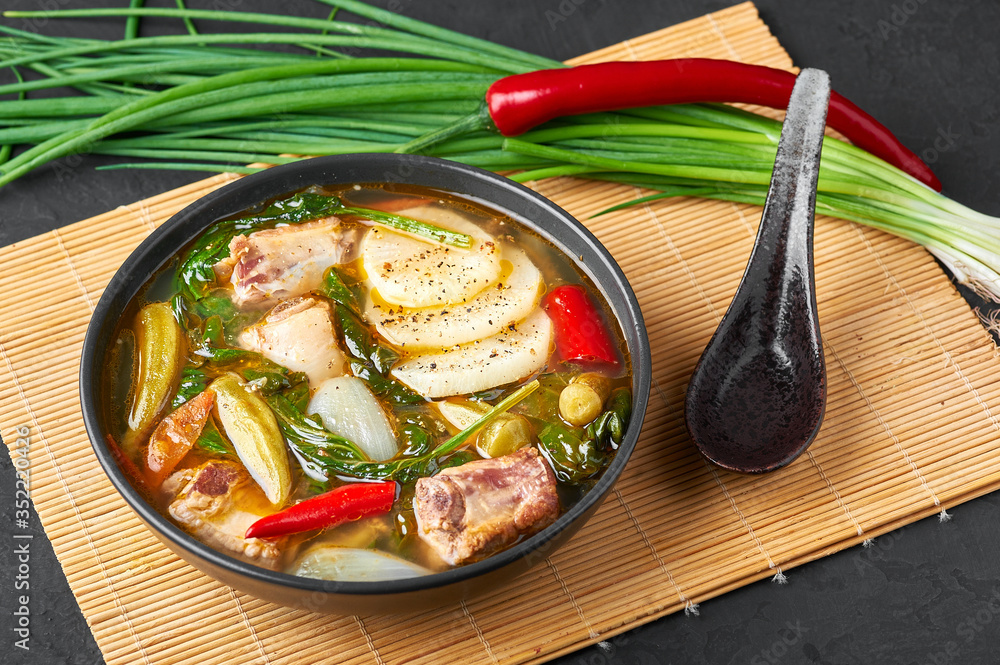 Sinigang na Baboy or Filipino Pork Meat Soup in black bowl on dark ...